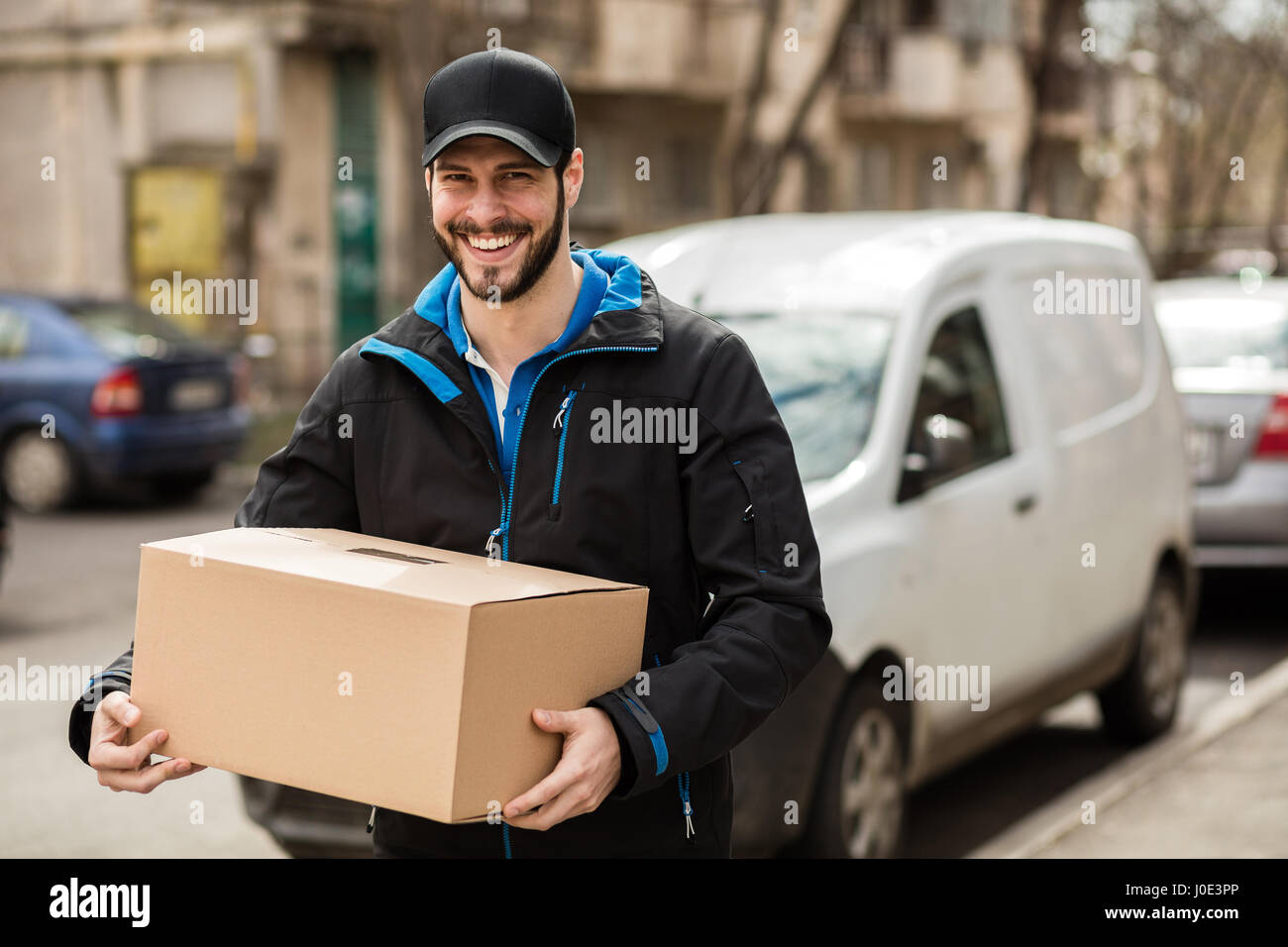 Delivery man with cap and cardboard in hands Stock Photo - Alamy