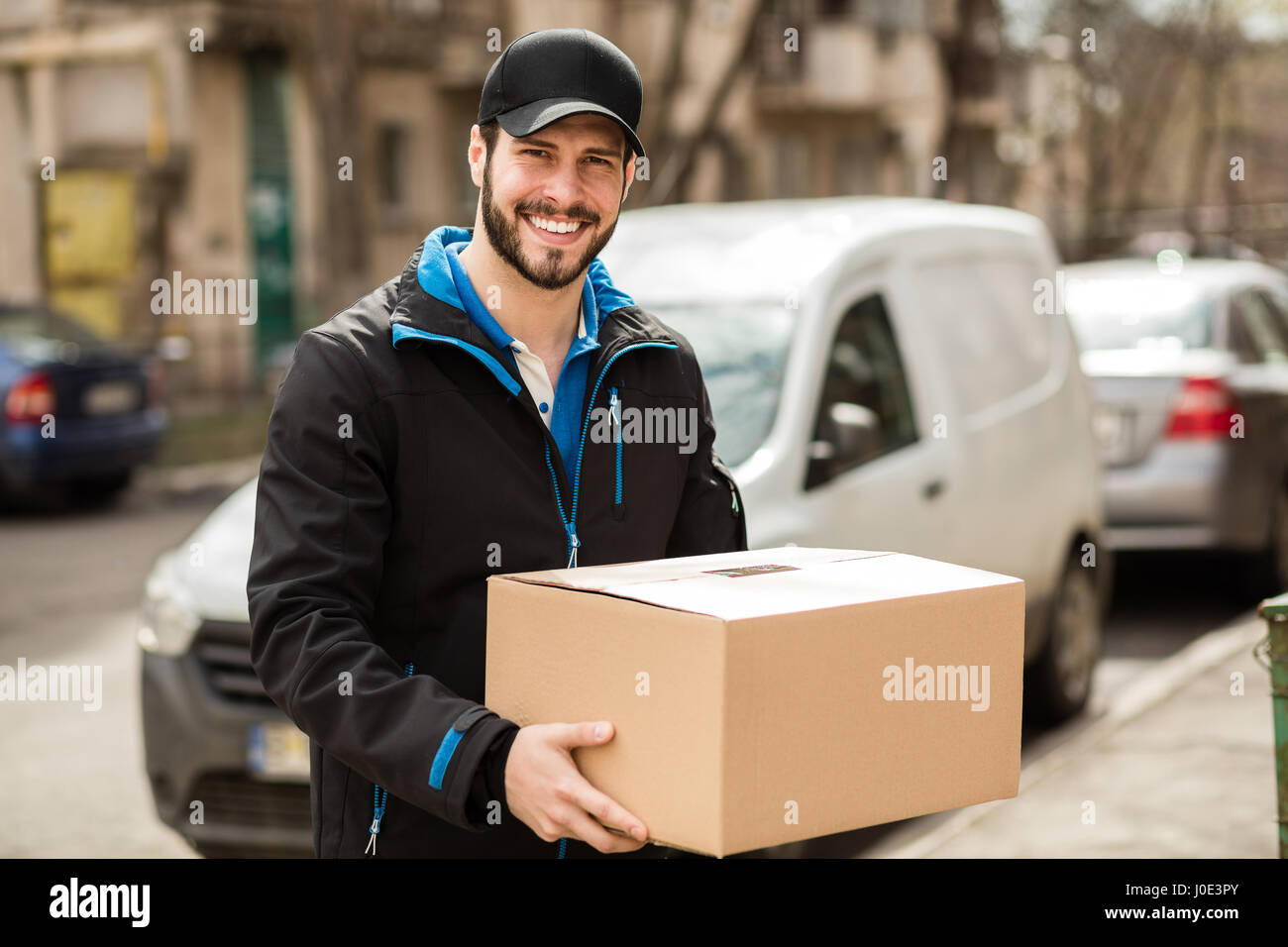 Delivery man with cap and cardboard in hands Stock Photo - Alamy