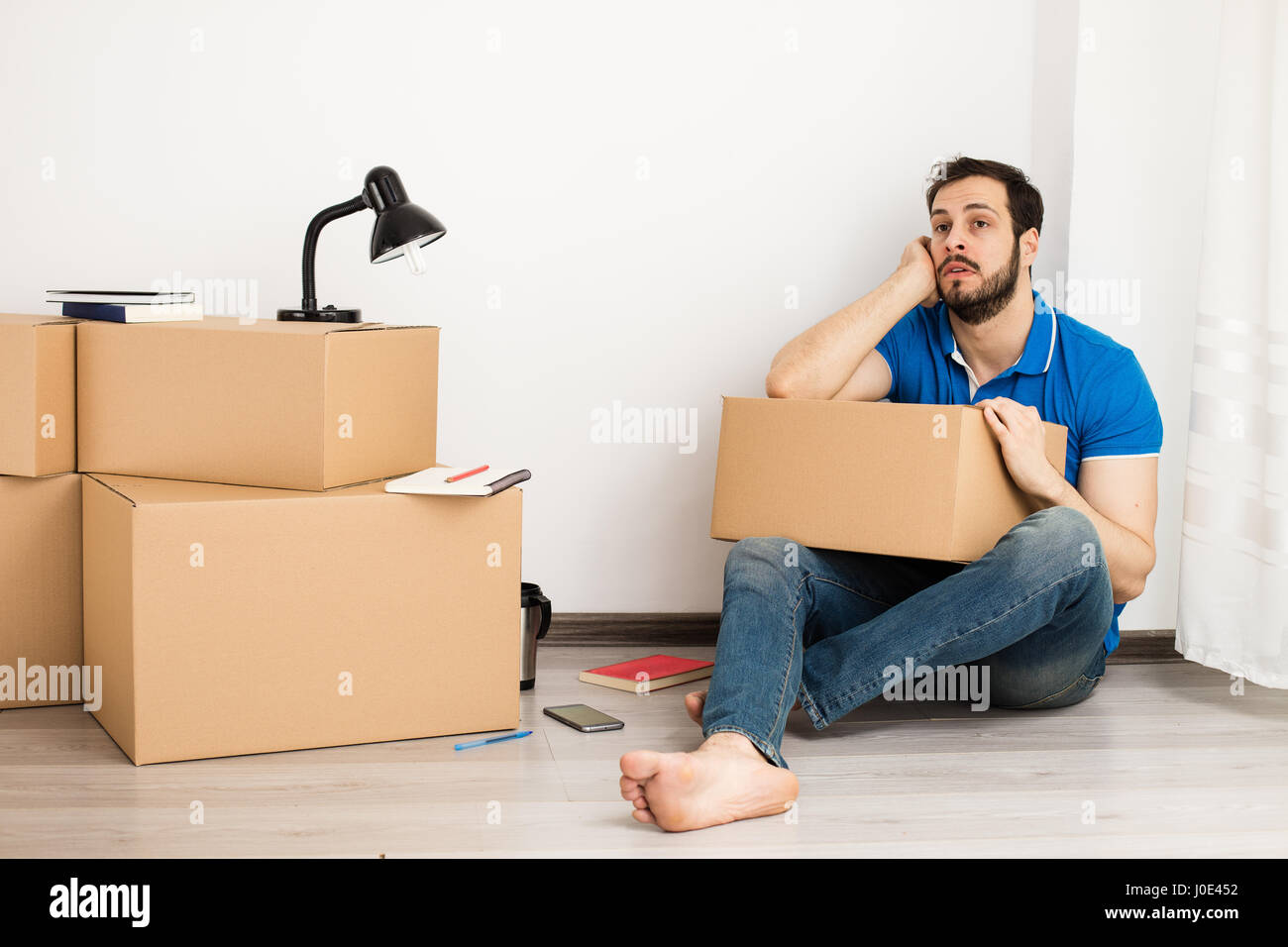 tired young man lying on the floor and holding his personal things ...