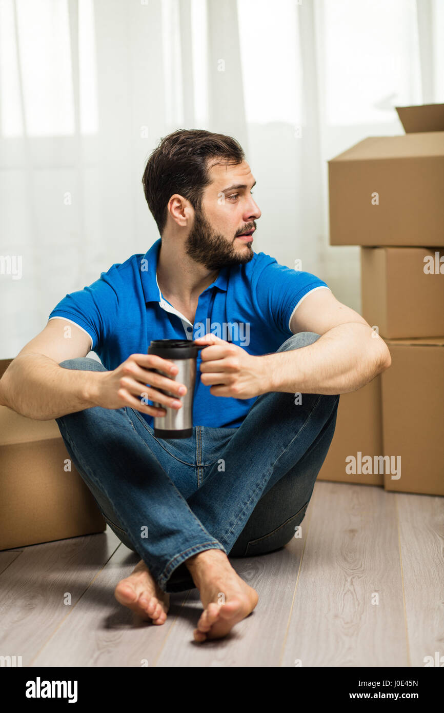 young man looking at his packing carton boxes that are waiting for him ...