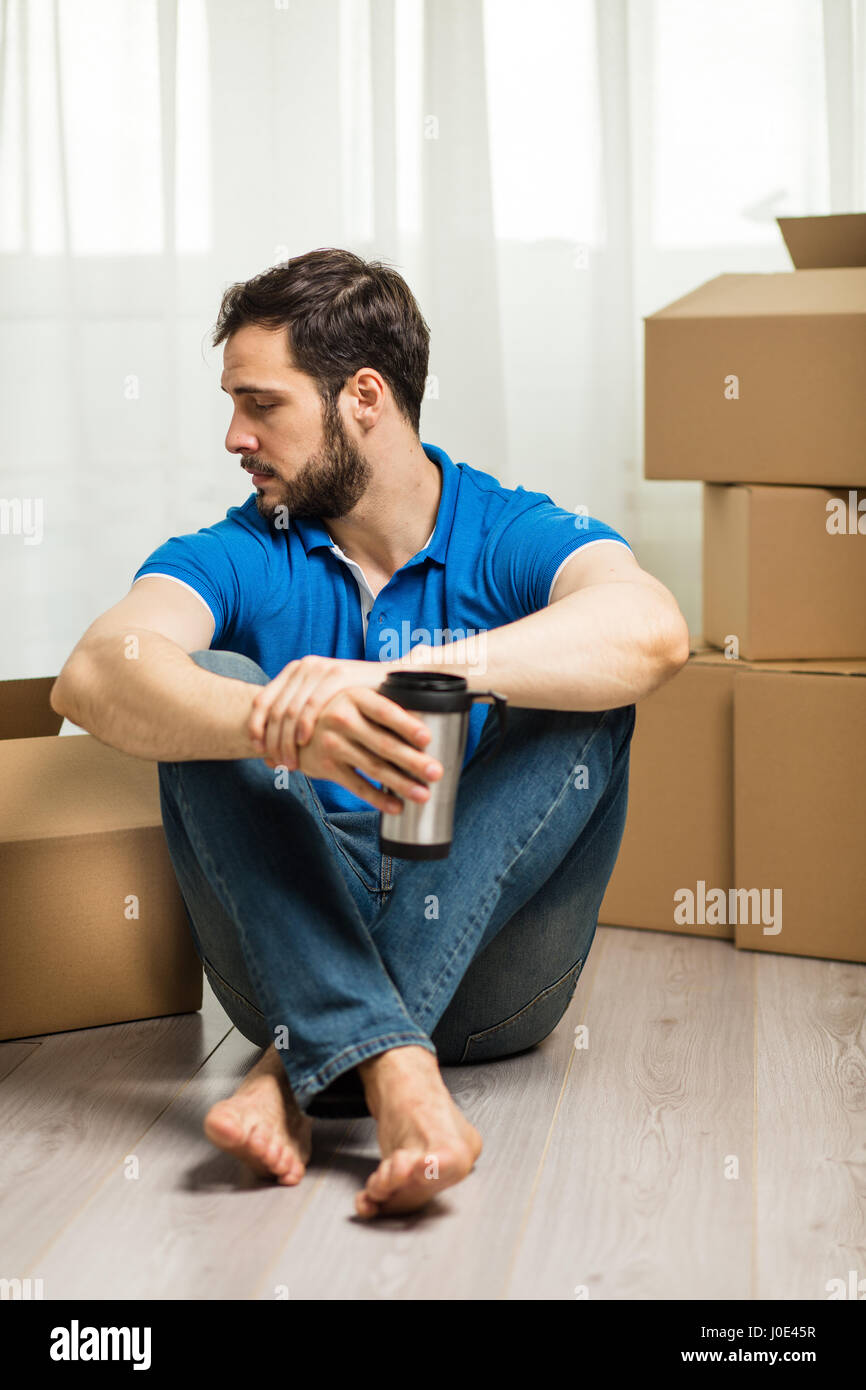 young man looking at his packing carton boxes that are waiting for him ...