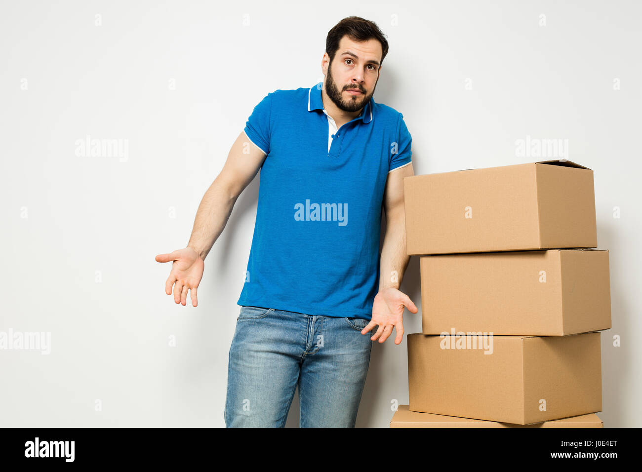 adult man standing next to a stack of carton boxes on white wall Stock ...
