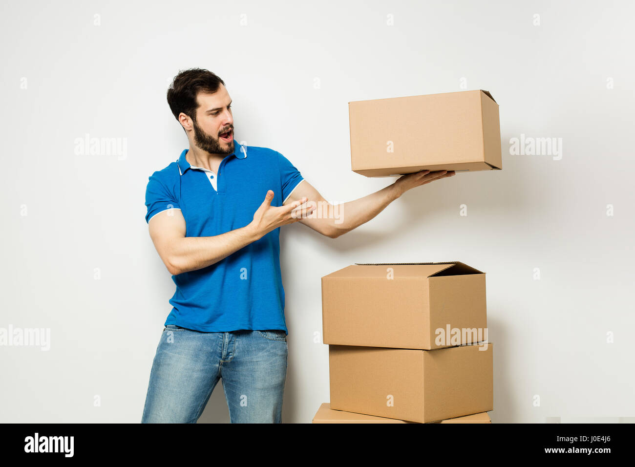 adult man holding a cardboard box over a stack of boxes and presenting ...