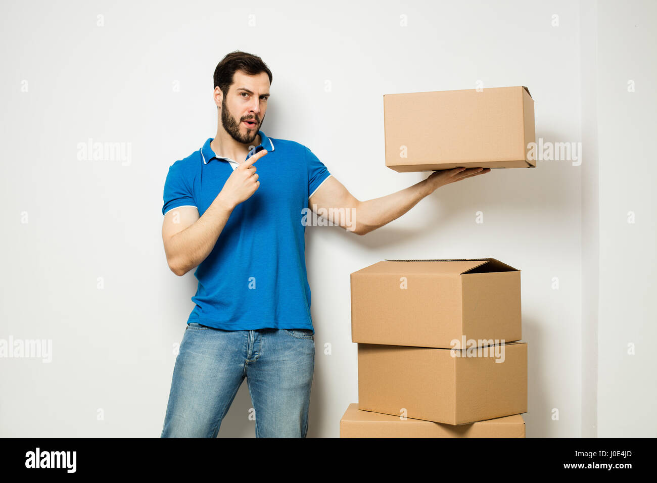adult man holding a cardboard box over a stack of boxes and presenting ...