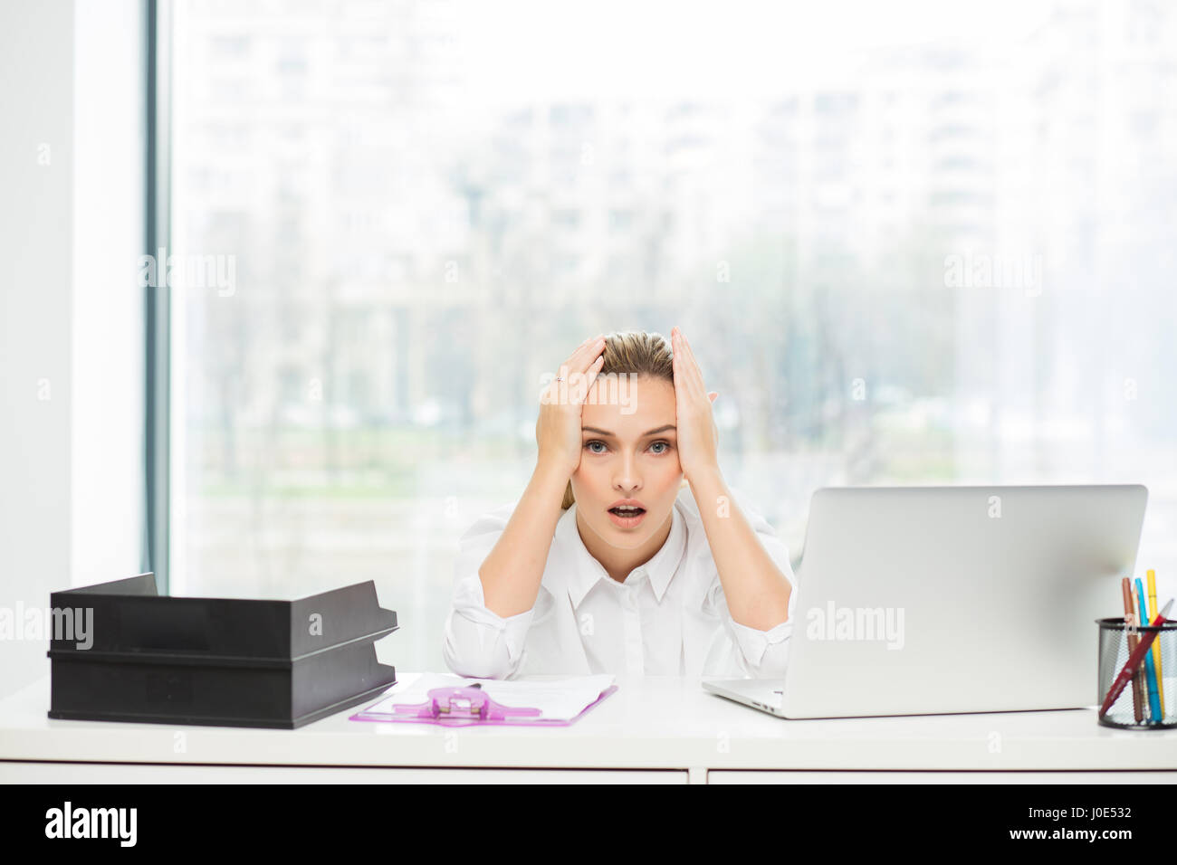 stressed woman behind the desk after a hard day work Stock Photo - Alamy