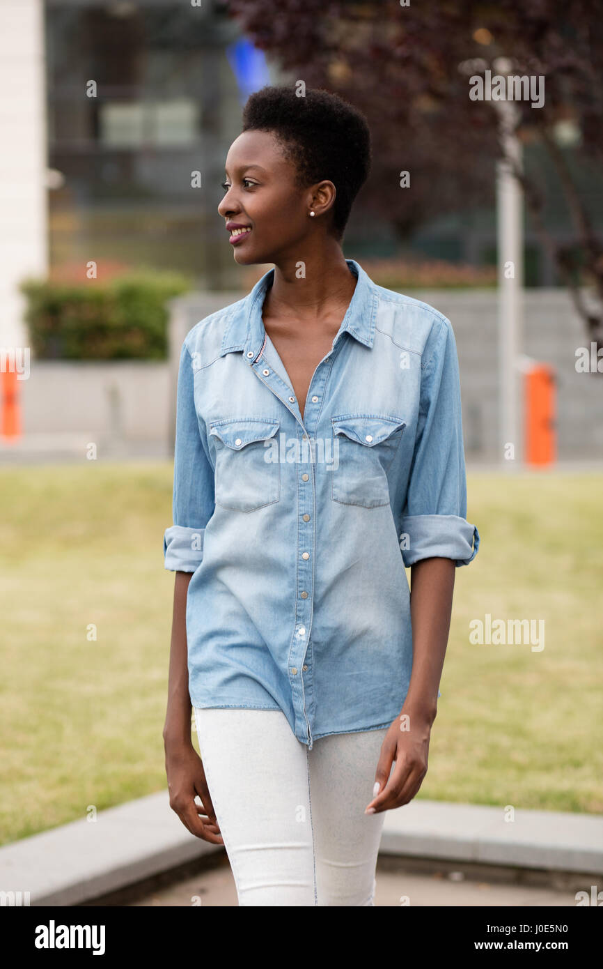 beautiful young and cool black lady walking on the street, in jeans ...