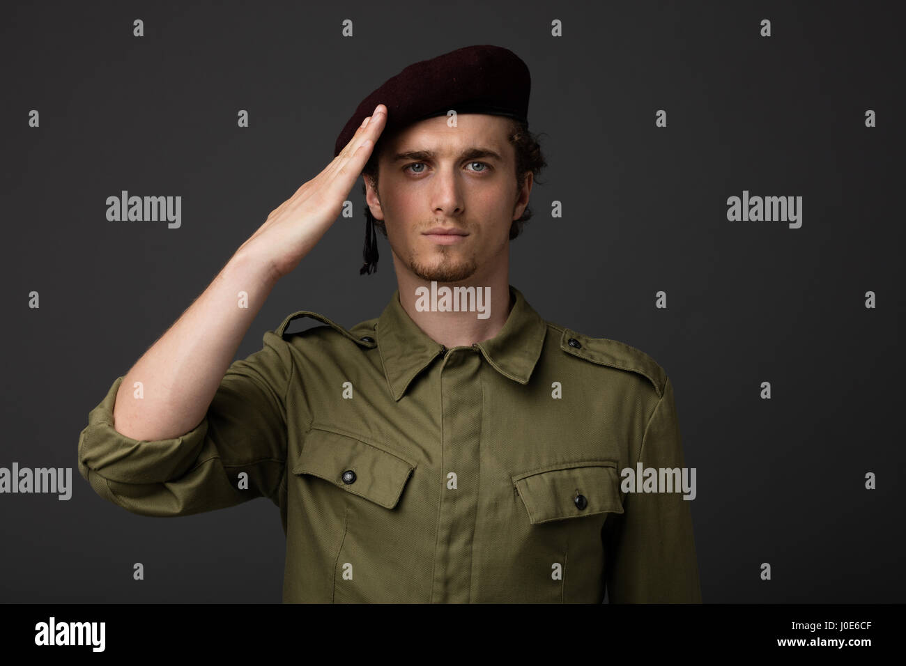 young military with red beret and green uniform on gray background ...