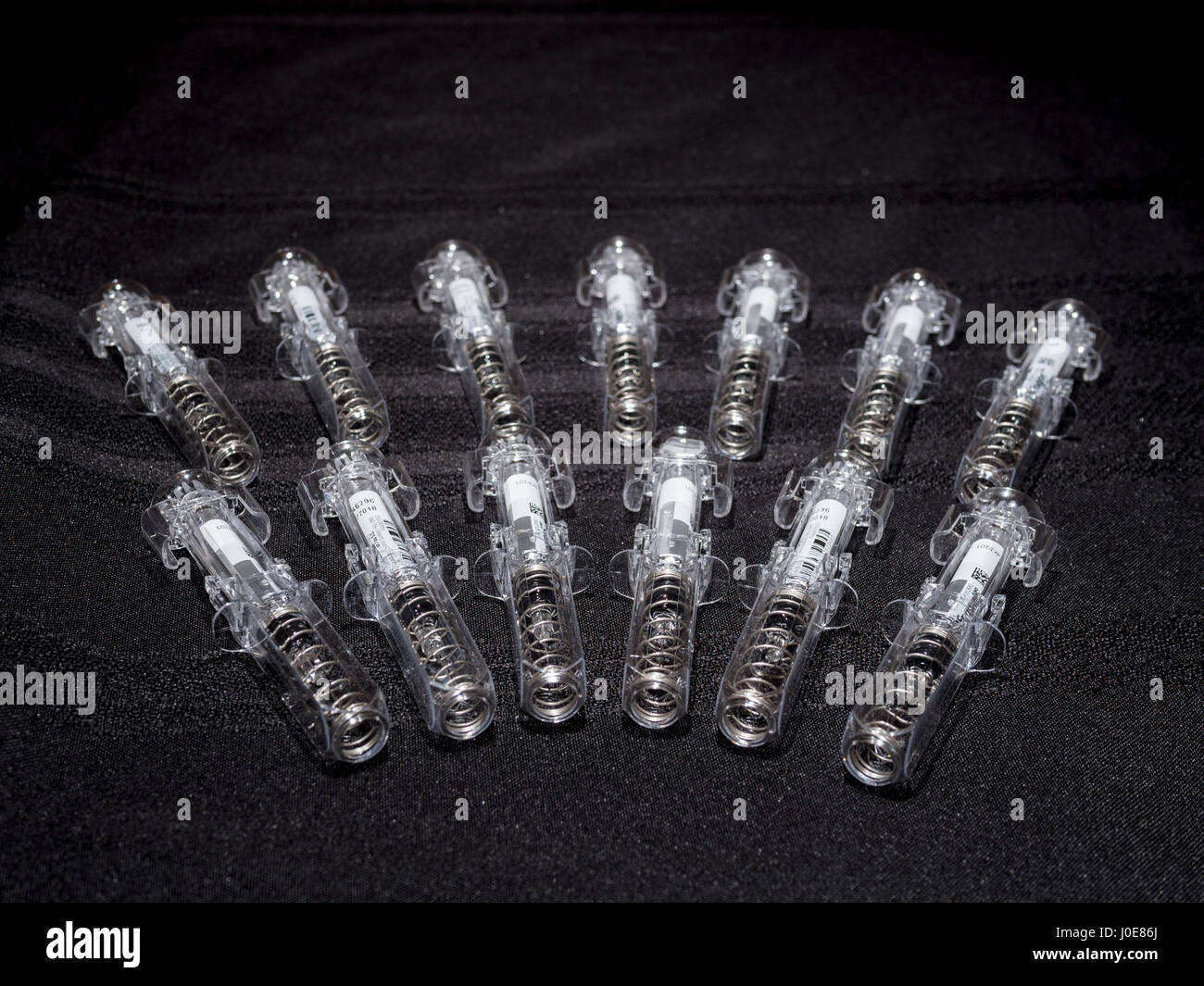 Thirteen Spent auto retraction Syringes. Arrayed on a dark background ...