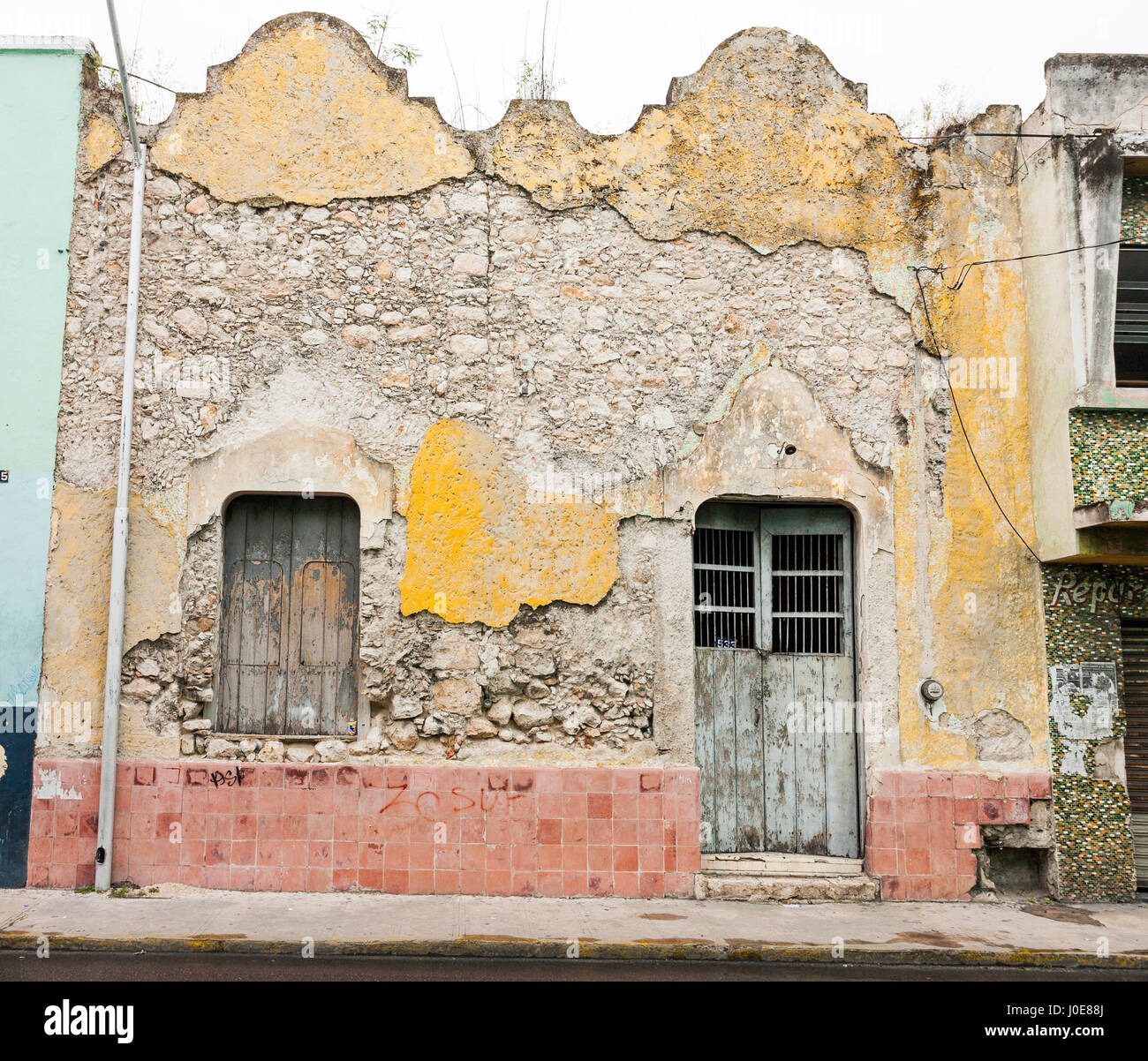 Facade of a crumbling Merada house. The yellow stucco crumbling off to ...