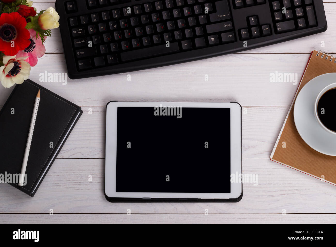 Overhead of office table with computer keyboard,tablet,notepad,coffee ...