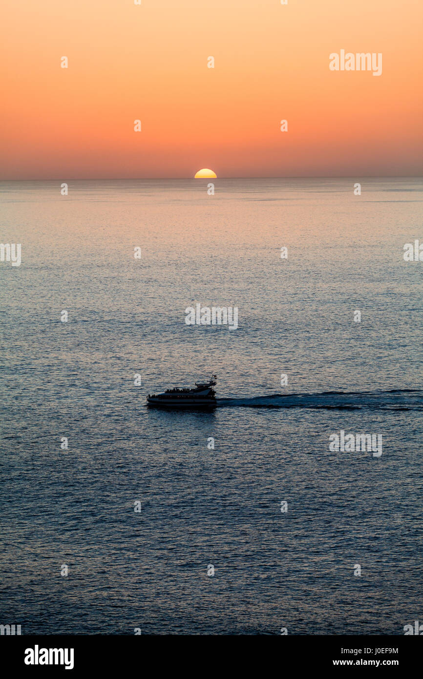 Small passenger ship passing across Atlantic ocean at the sundown ...
