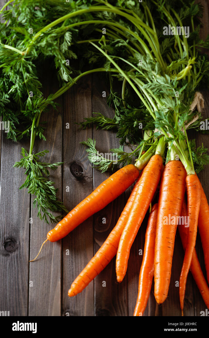 Heap of ripe carrots with leaves on dark rustic table Stock Photo - Alamy