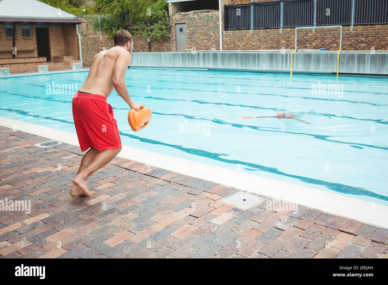Rear view of lifeguard jumping into a swimming pool to rescue drowning ...