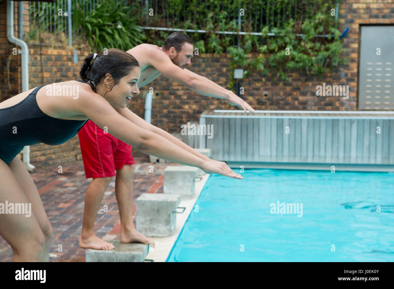 Side view of couple preparing to dive in pool Stock Photo - Alamy