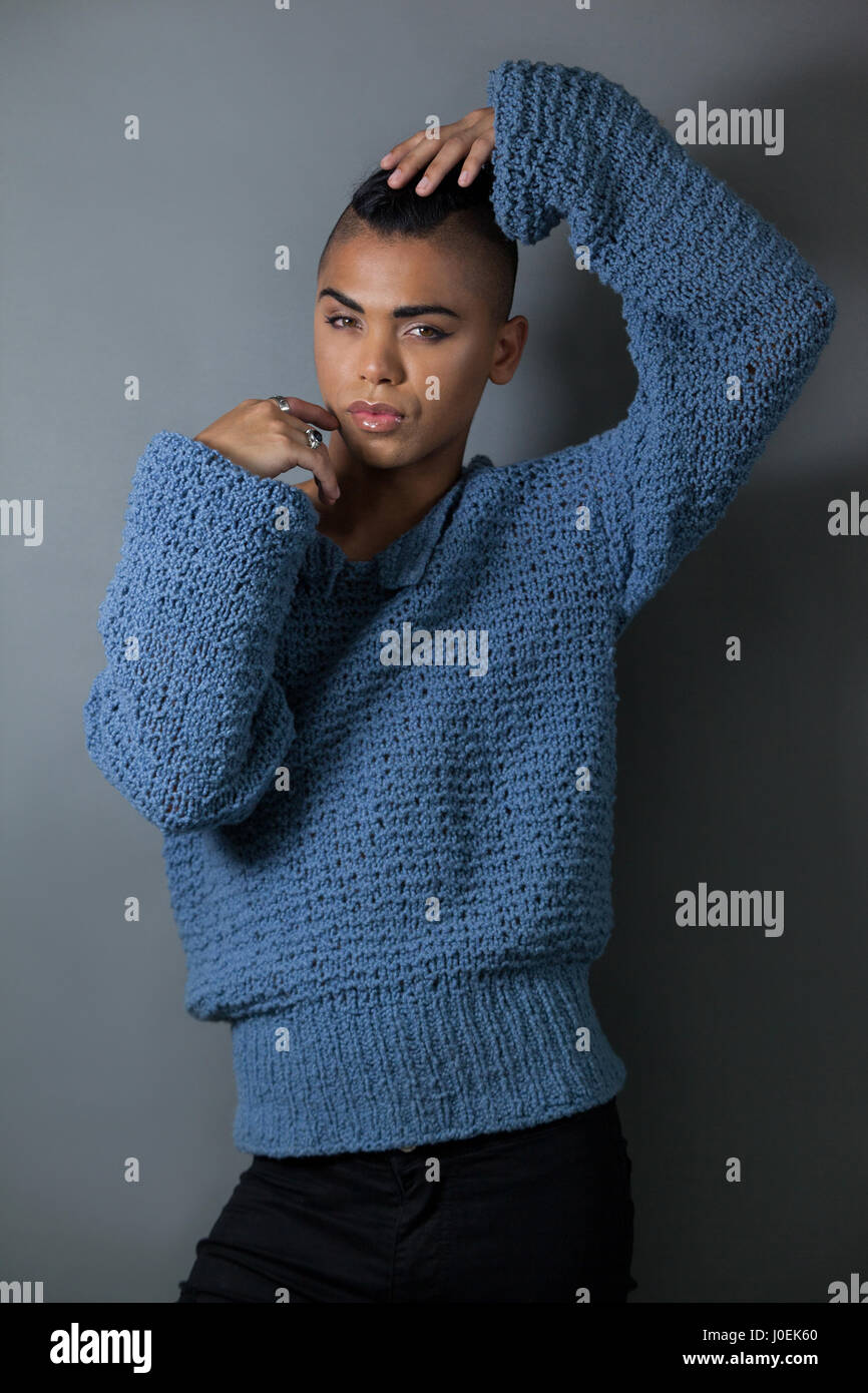 Portrait of confident transgender posing while standing against gray ...