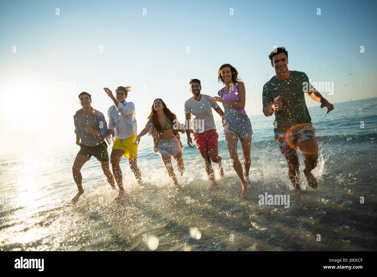 Full length of happy friends running on shore at beach Stock Photo - Alamy