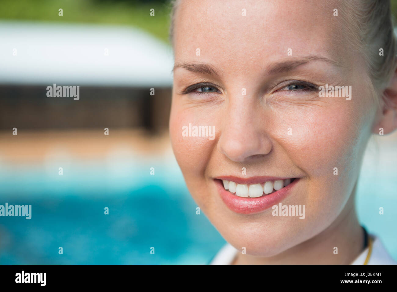 Portrait of smiling female coach standing near poolside at the leisure ...