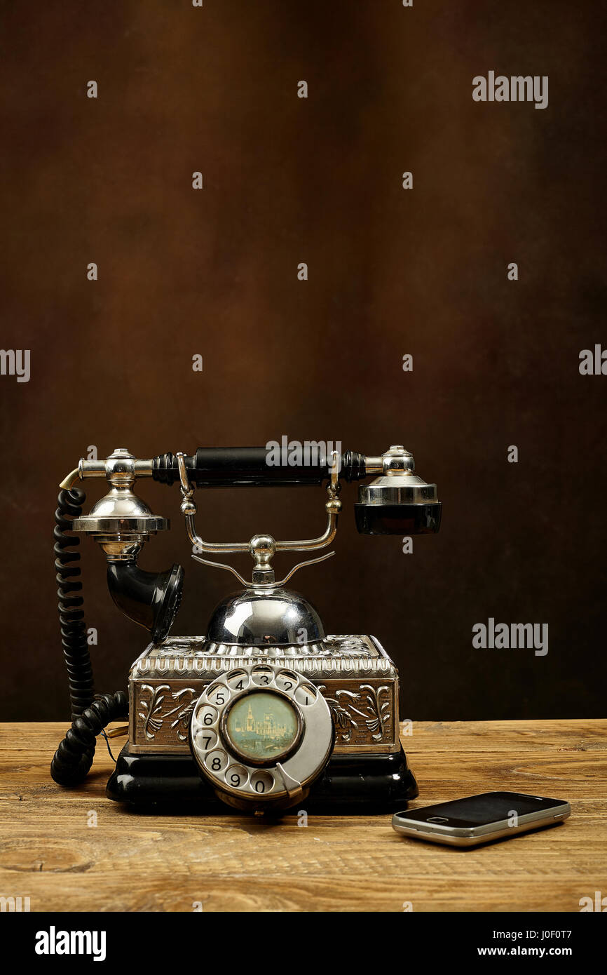 Vintage telephone on wooden table and a mobile phone Stock Photo - Alamy