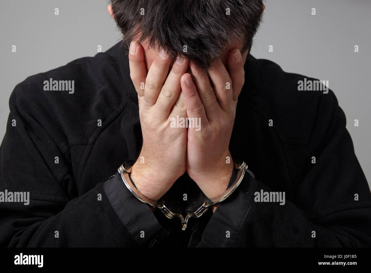 Closeup view of handcuffed man hidding his face Stock Photo - Alamy