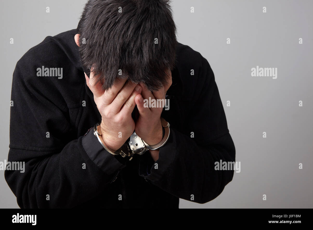 Closeup view of handcuffed man hidding his face Stock Photo - Alamy
