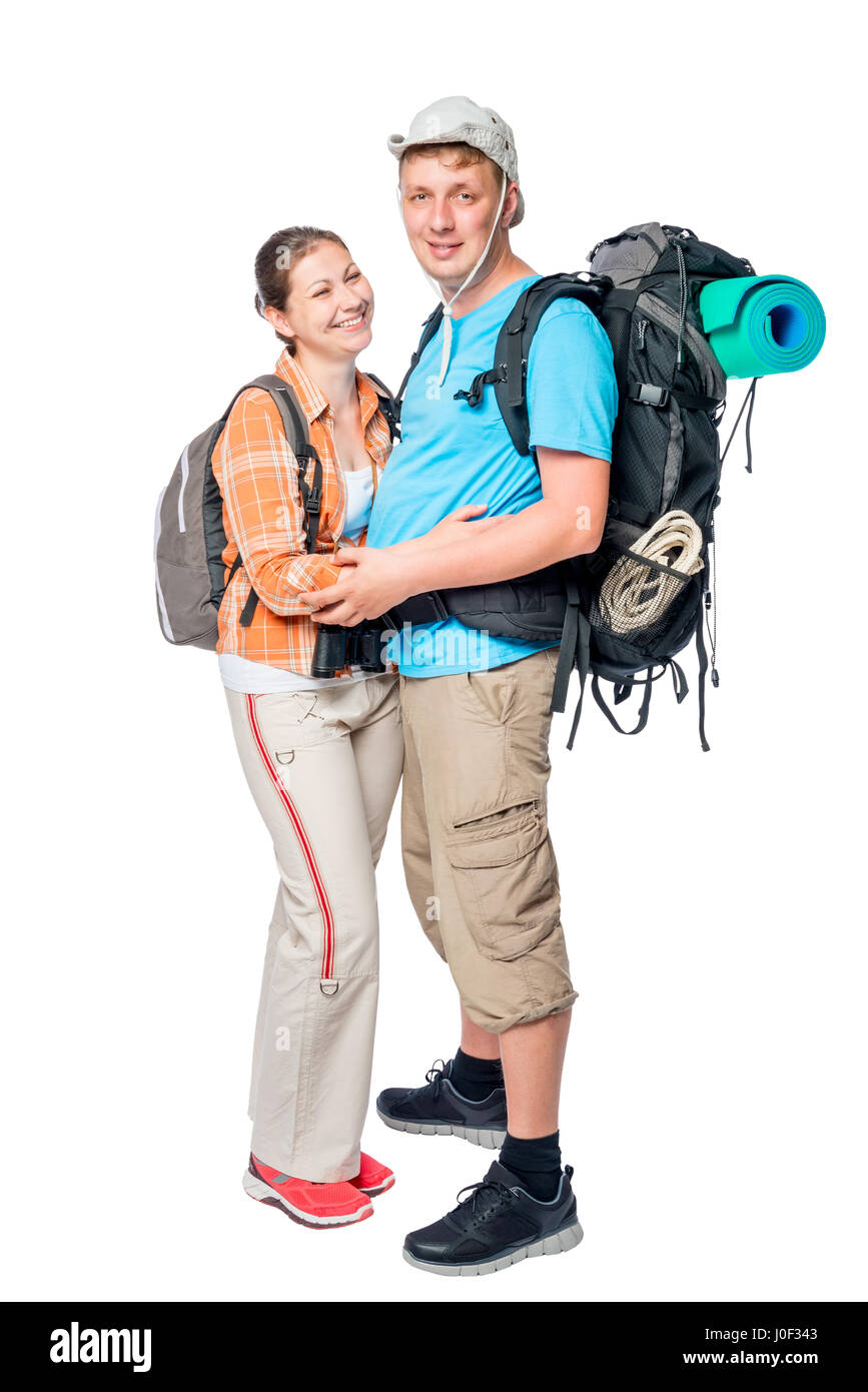 Hugging couple of young tourists with backpacks posing on white ...