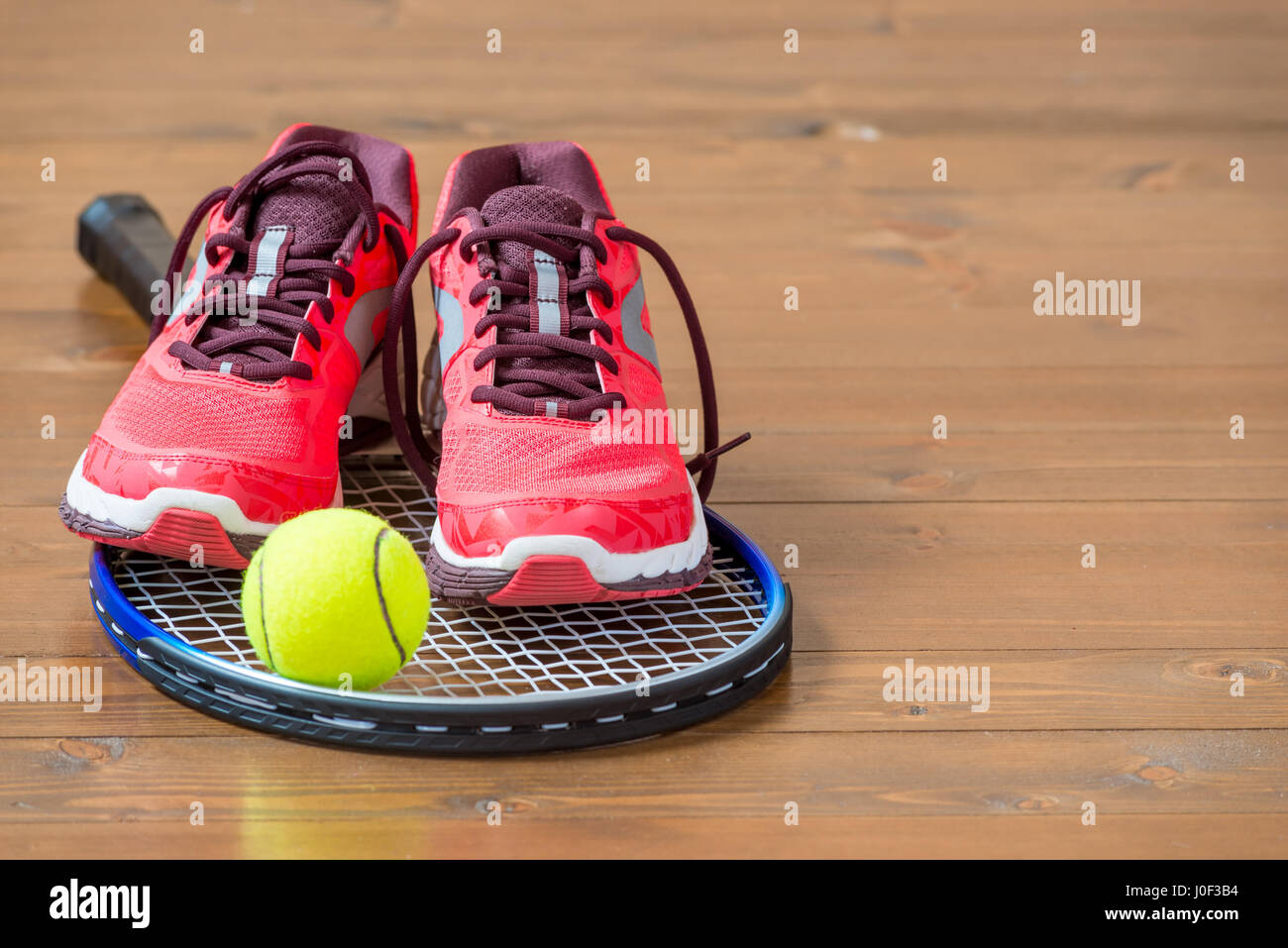 Pair of women's sneakers on a tennis racket on a wooden floor Stock ...
