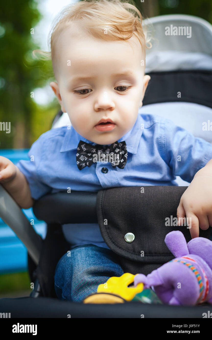 little boy sitting in a stroller. baby for a walk in a pram. summer ...