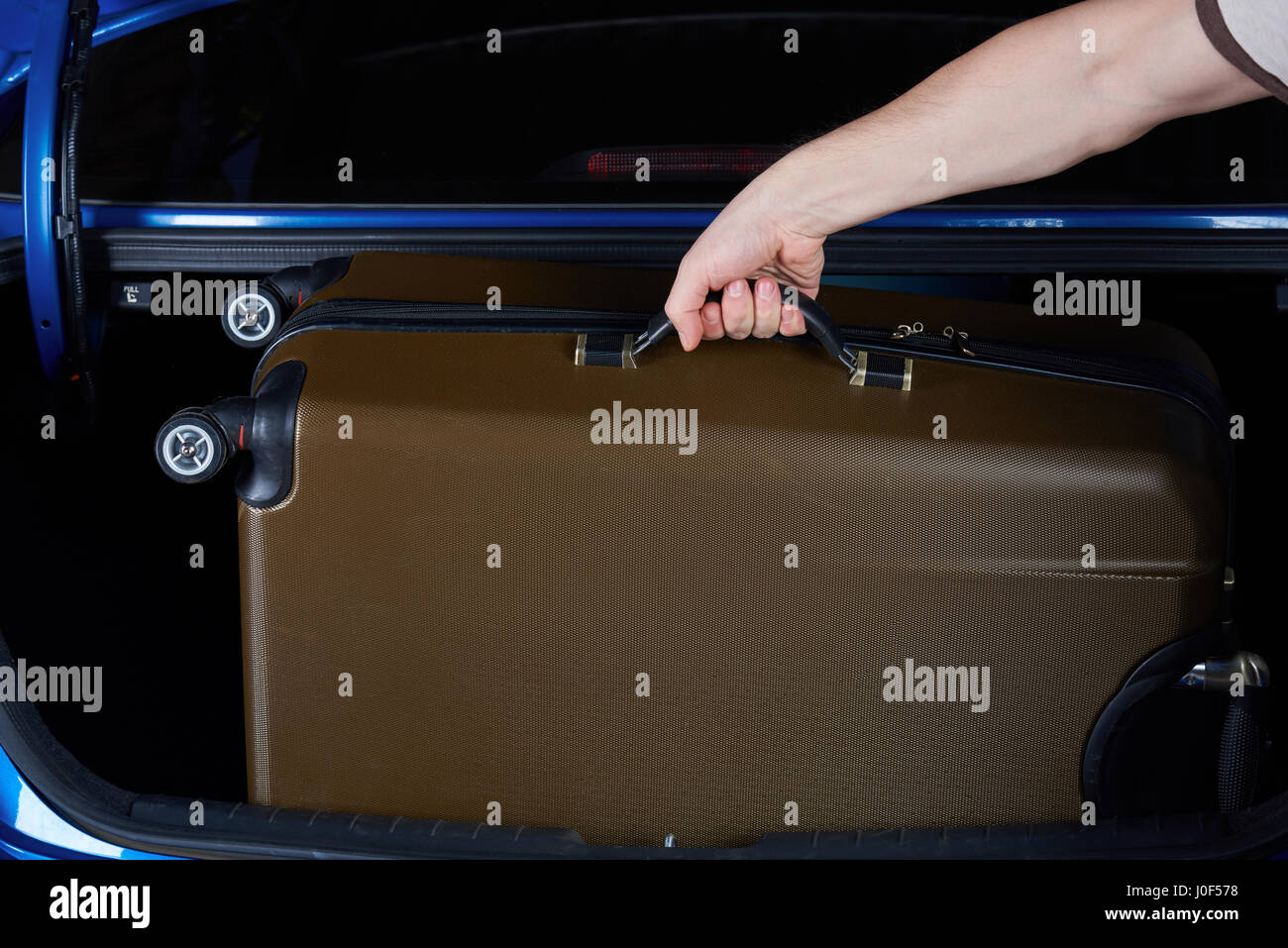 Hand take luggage from car trunk close-up. Taking suitcase from vehicle ...