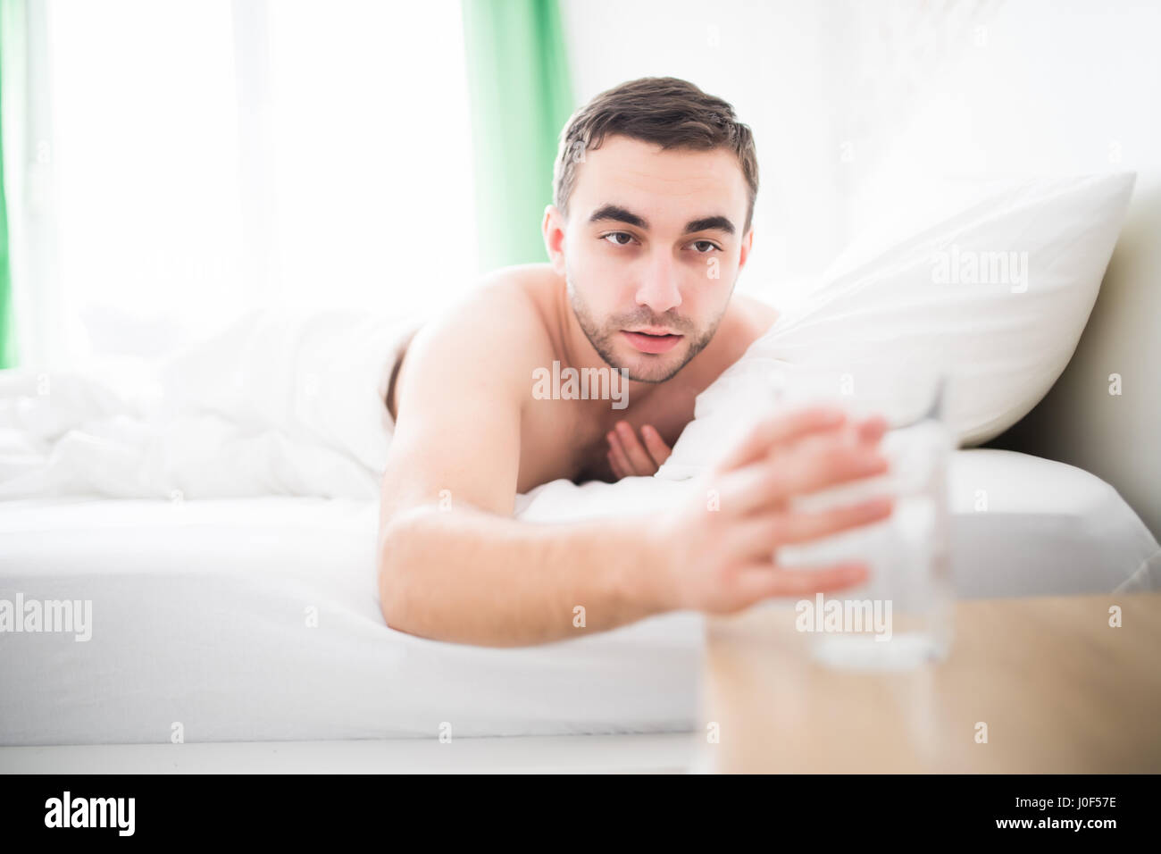 Handsome man wake up in the morning and extend to drink a glass of ...