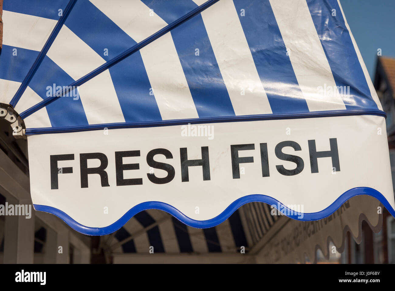 A fresh fish shop sign on a blue and white stripped awning in Cromer ...