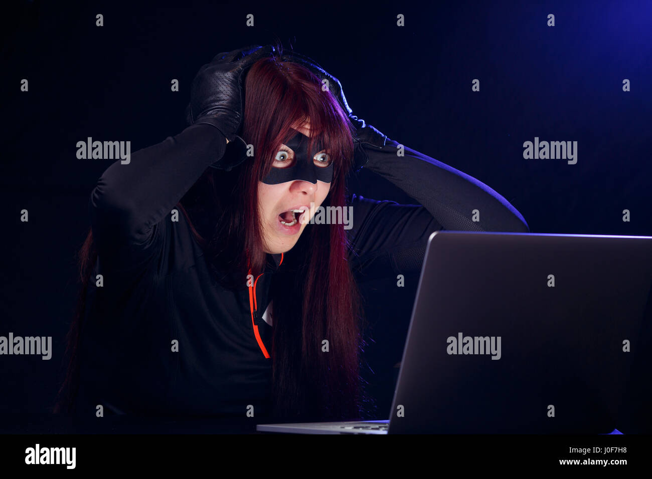 Surprised hacker with hands near head next to laptop Stock Photo - Alamy