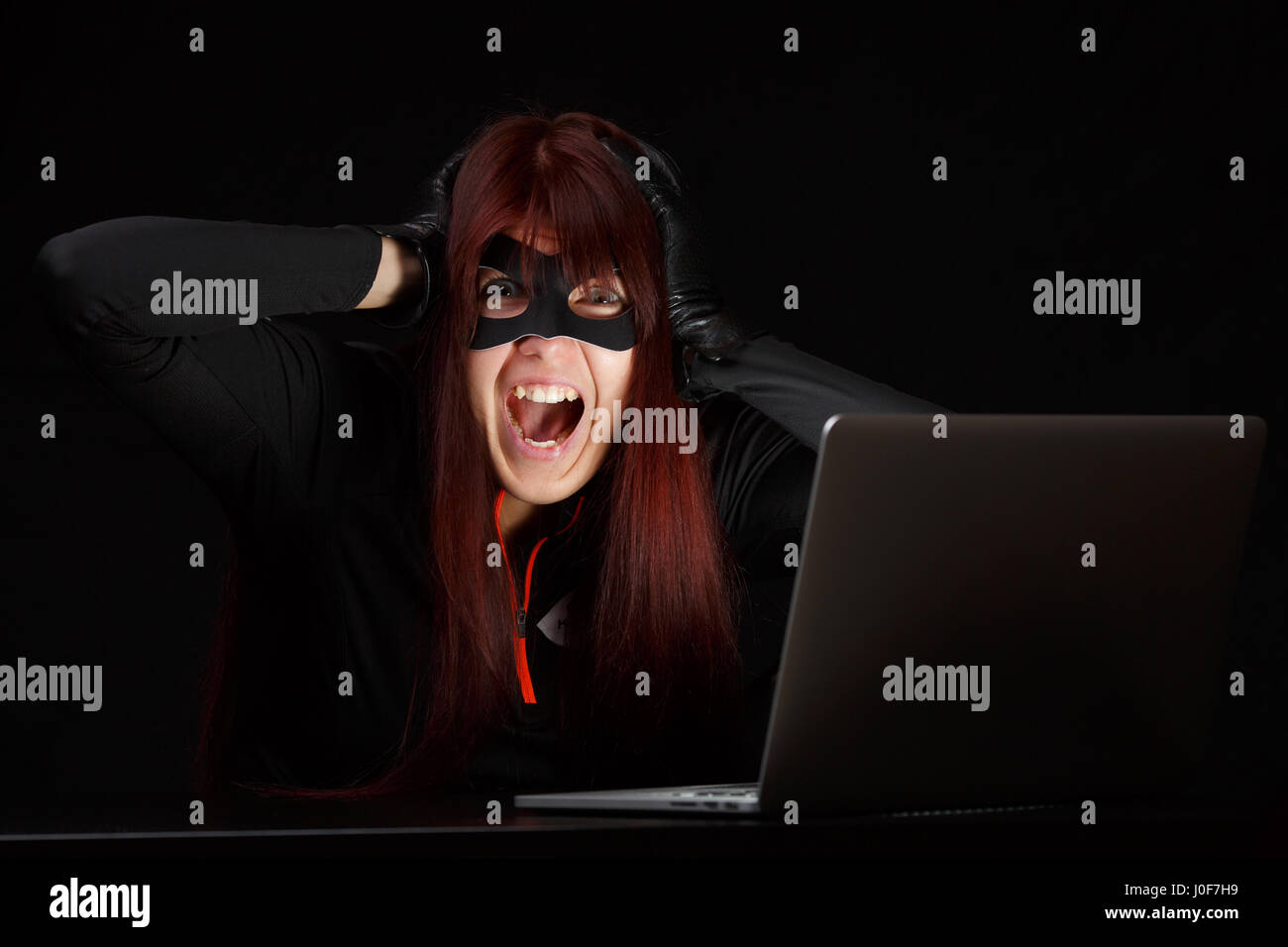 Brunette hacker in black mask screaming at computer Stock Photo - Alamy