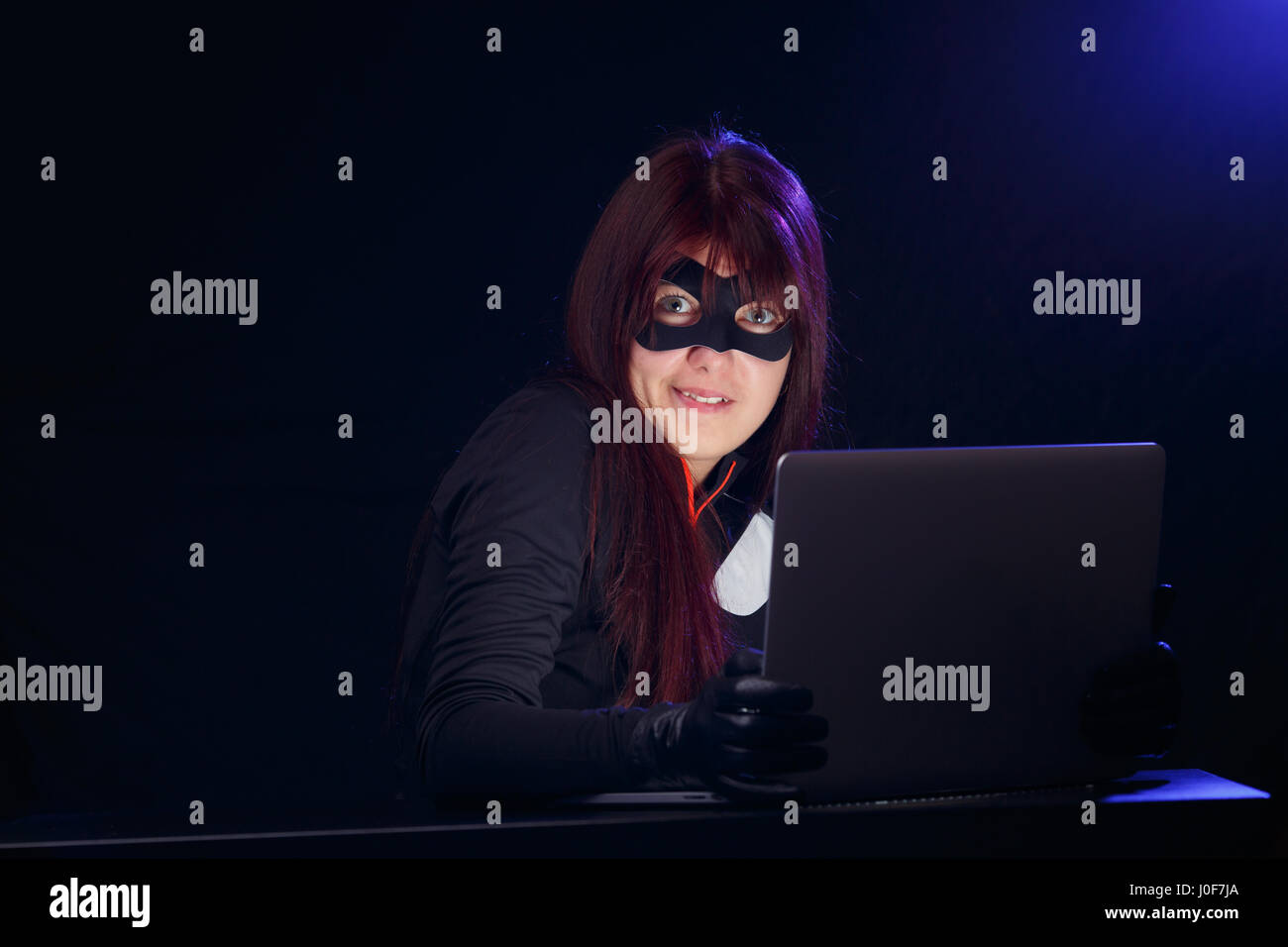 Woman spy in black mask by computer at night Stock Photo - Alamy