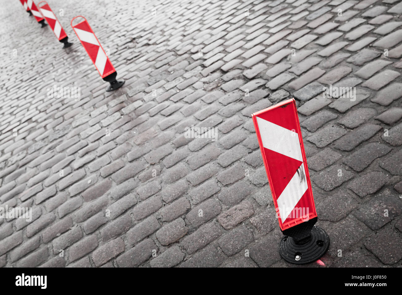 Vertical red and white striped caution road signs stand in a row on ...