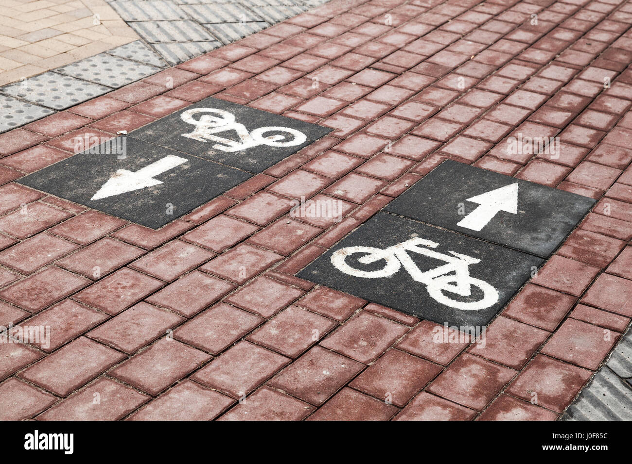 Bicycle lane, road marking with arrows and bike icons over brown cobble ...