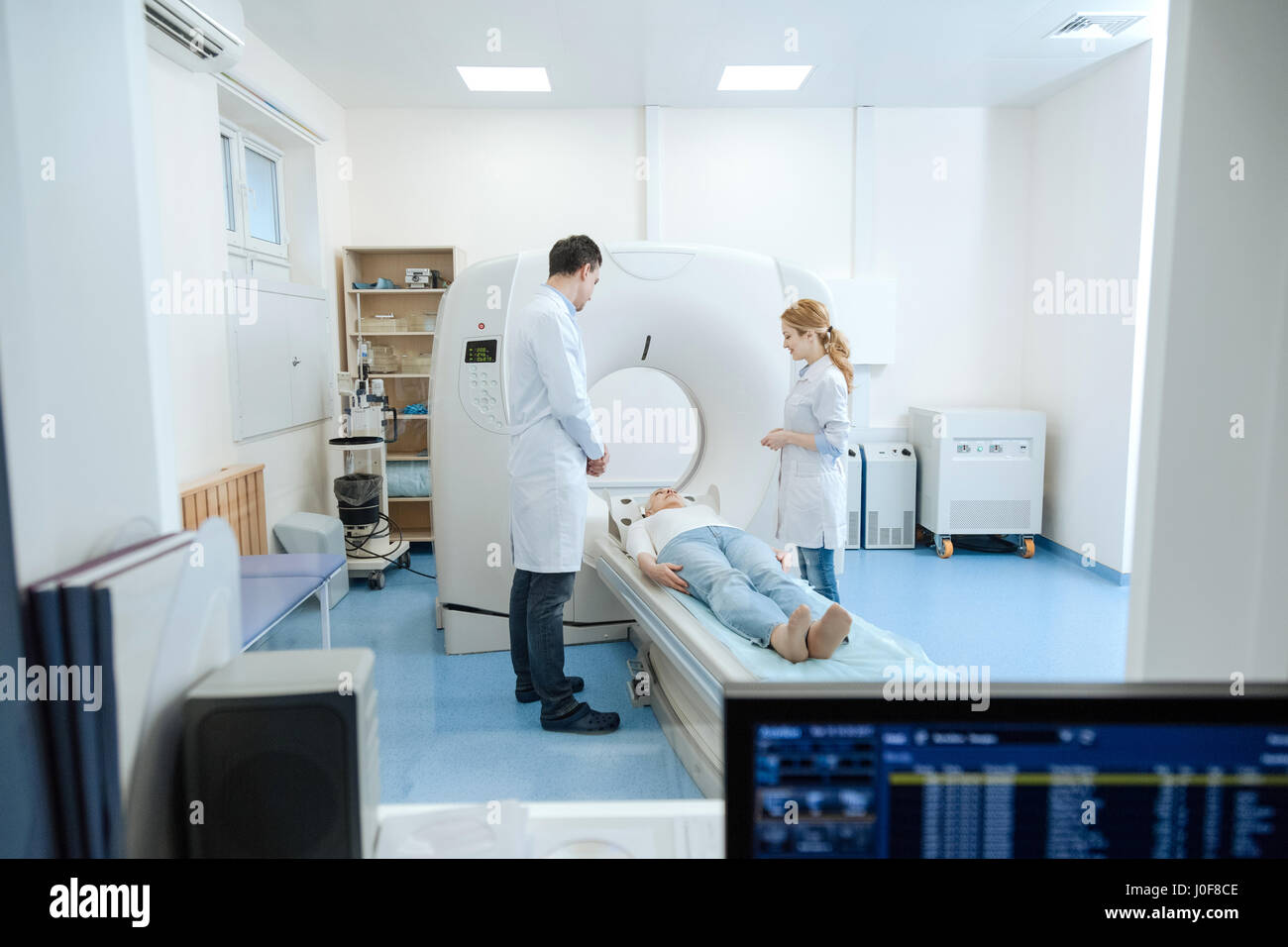 Nice pleasant doctors standing over their patient Stock Photo - Alamy