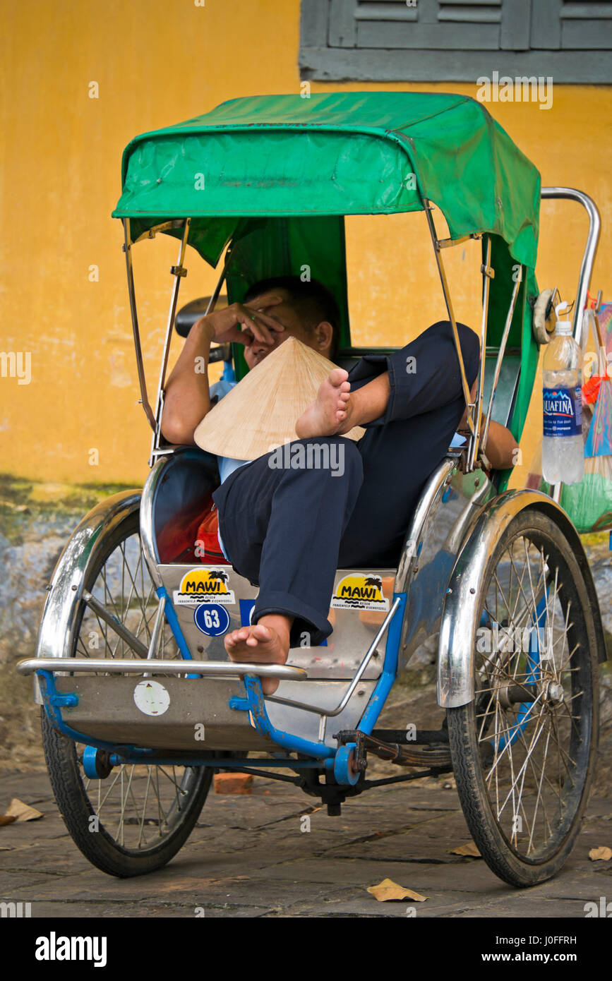 Vertical view of a cyclo driver relaxing in Hoi An, Vietnam Stock Photo ...