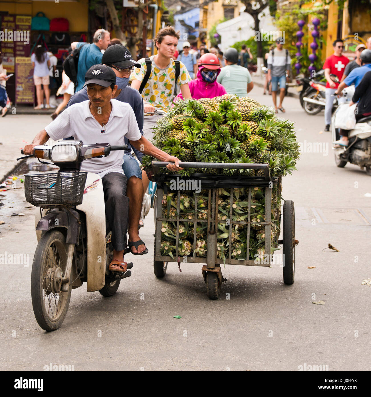 Square view of people riding a motorbike and pulling a cart full of ...