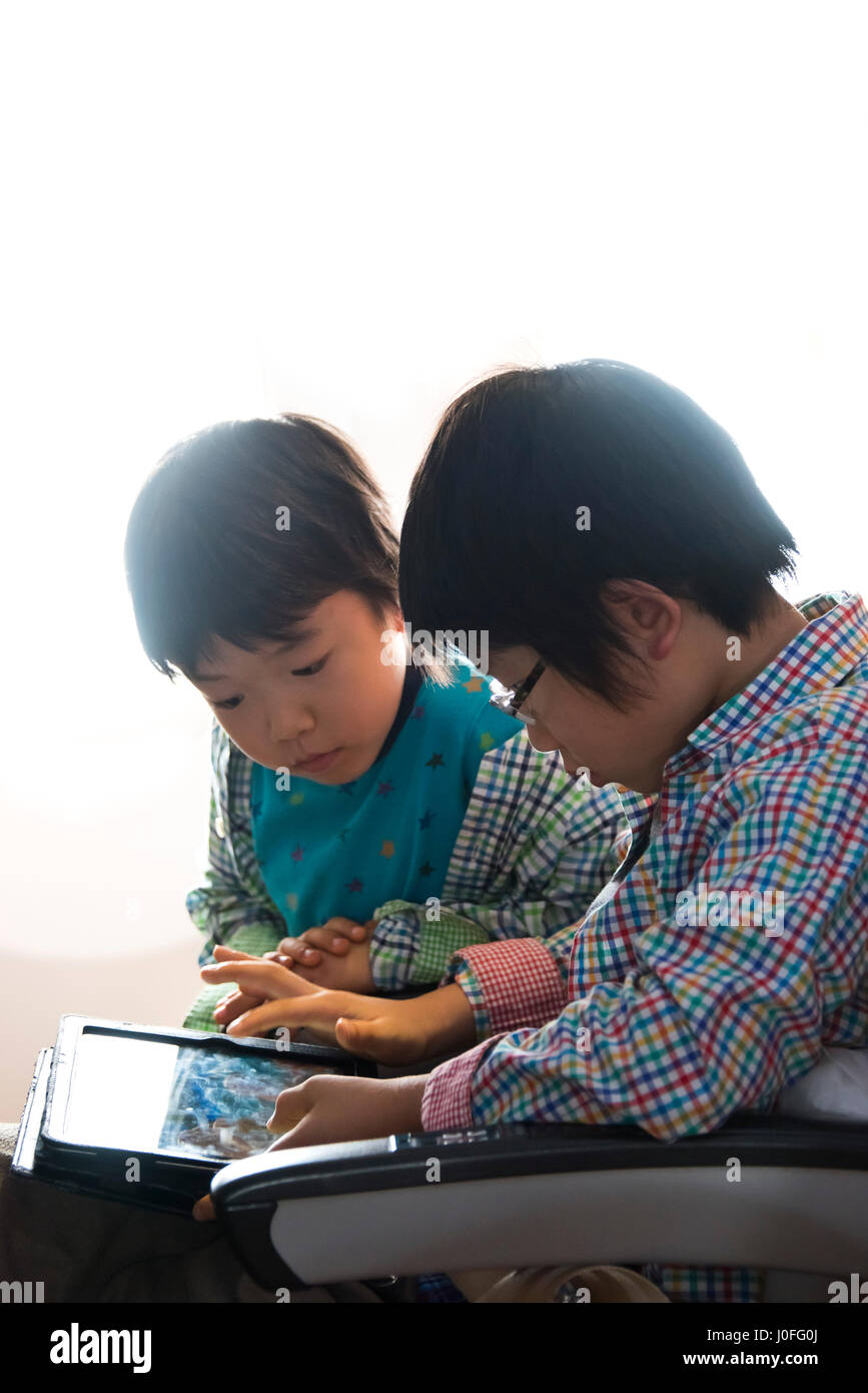 Vertical quare portrait of two young boys playing on an ipad together ...