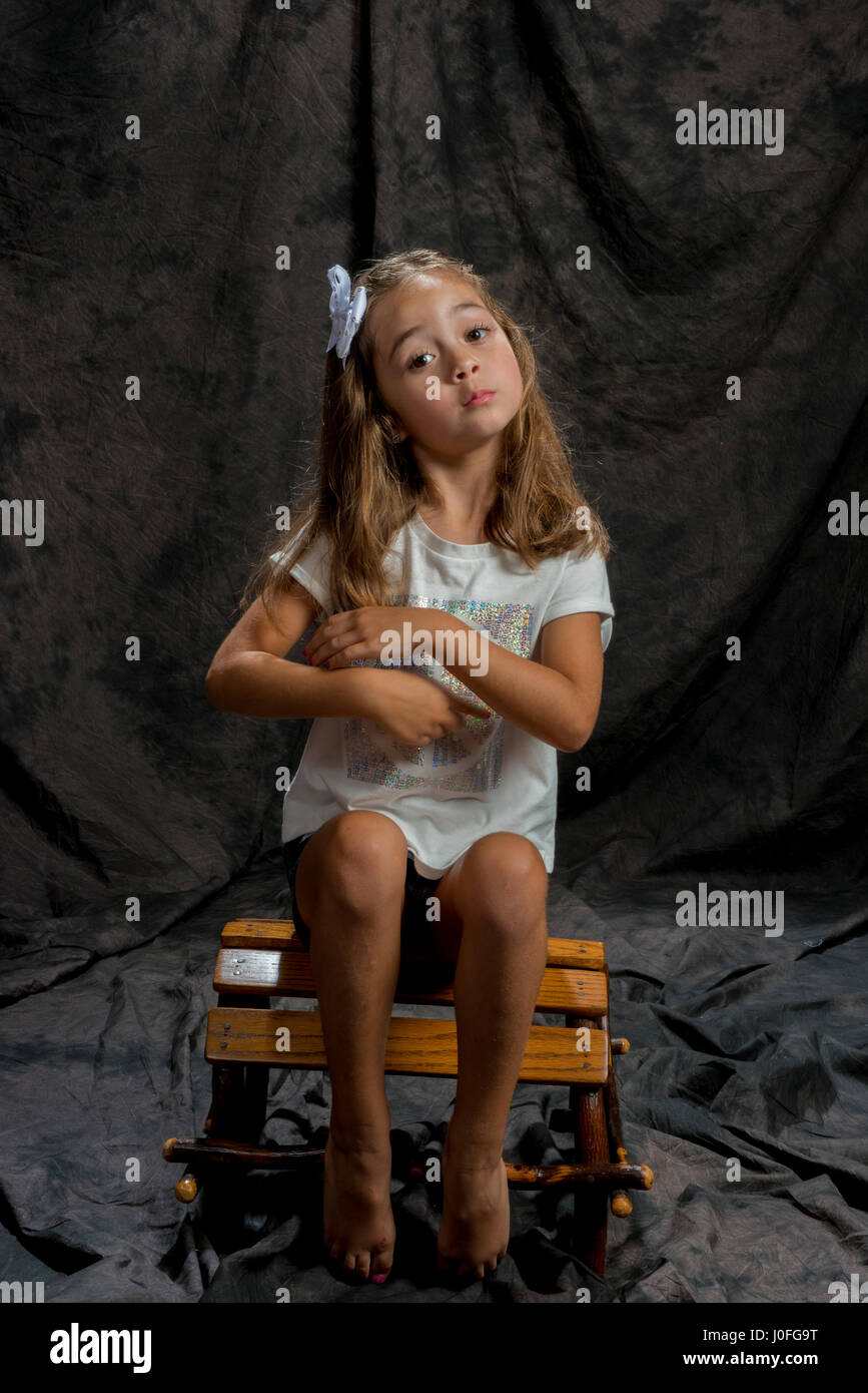 little girl modeling in studio brown background siting on a wood chair ... little girl modeling in studio brown background siting on a wood chair ...