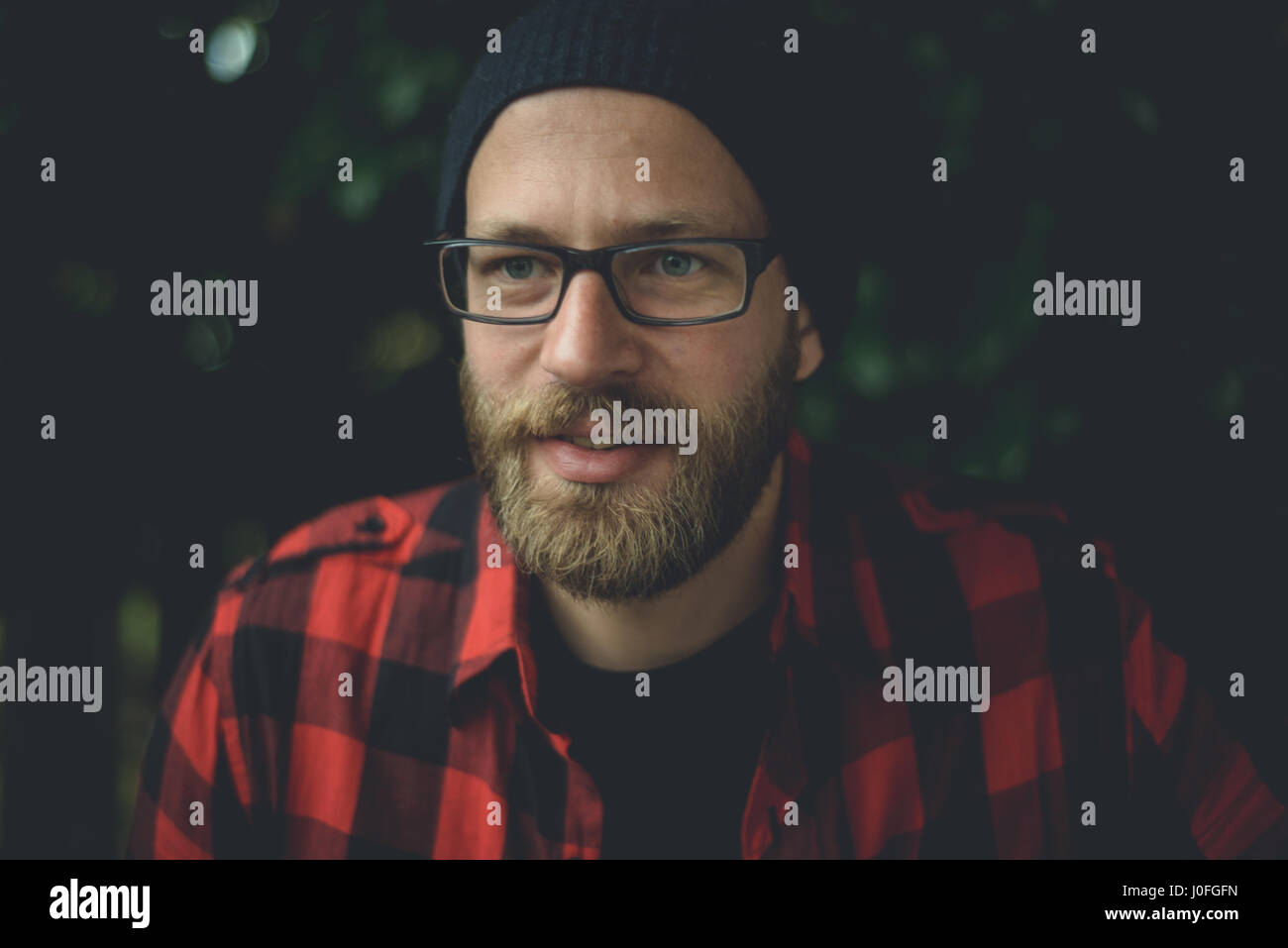 Authentic portrait of a handsome hipster man sitting on porch outdoors ...