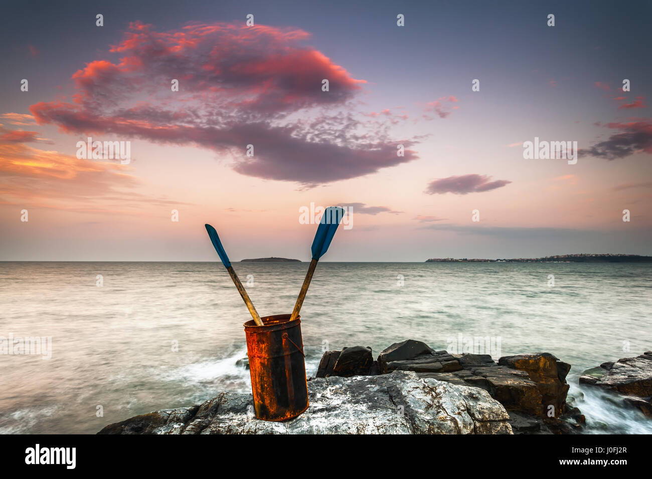 Rusty bucket with two oars by the sea shore at sunset Stock Photo - Alamy