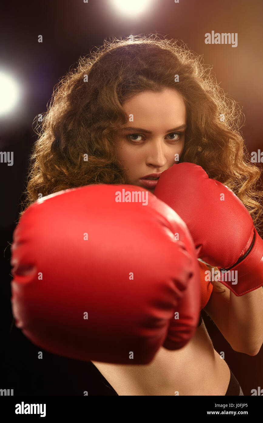 Beautiful young sportswoman in boxing gloves punching at camera Stock ...