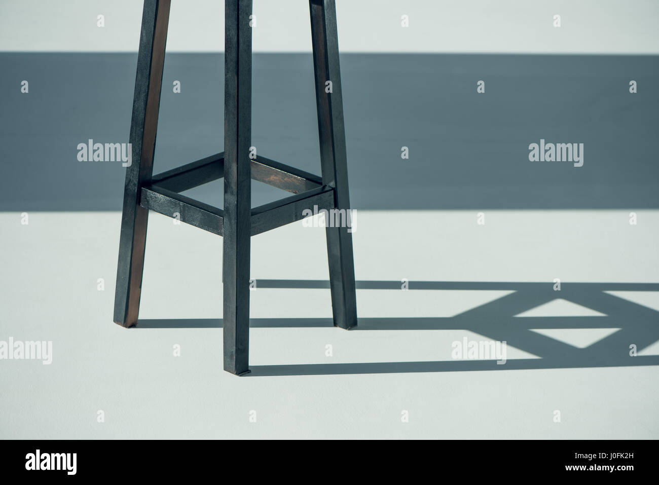 cropped shot of wooden bar stool and shadow on grey Stock Photo - Alamy