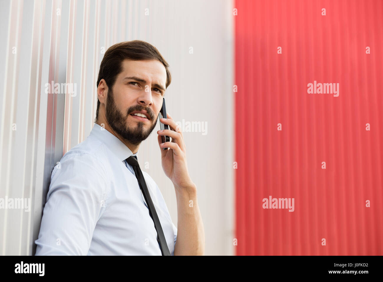 handsome office man talking at cellphone outside in a working break ...