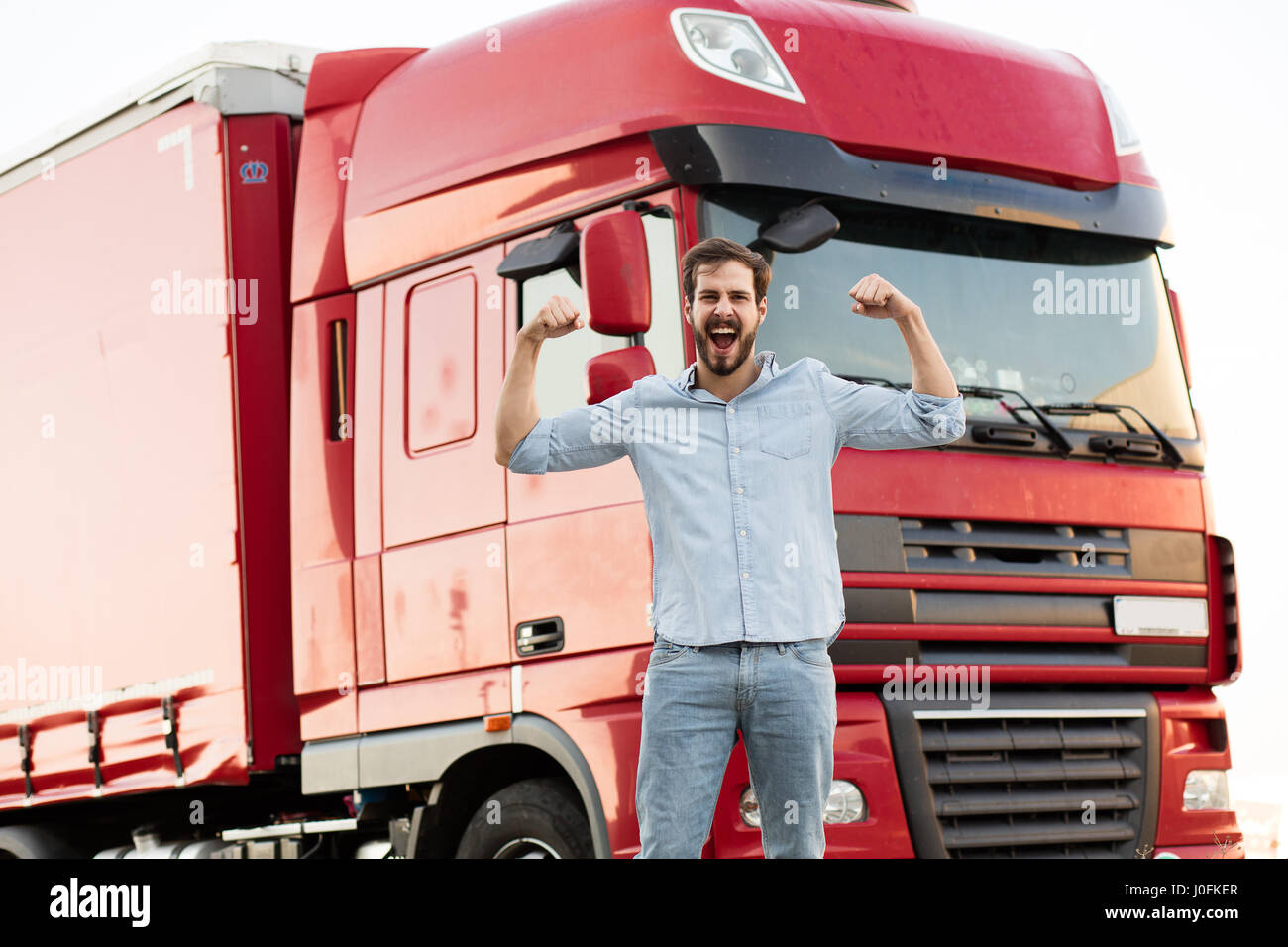 strong masculine truck driver standing outside and showing his muscle ...