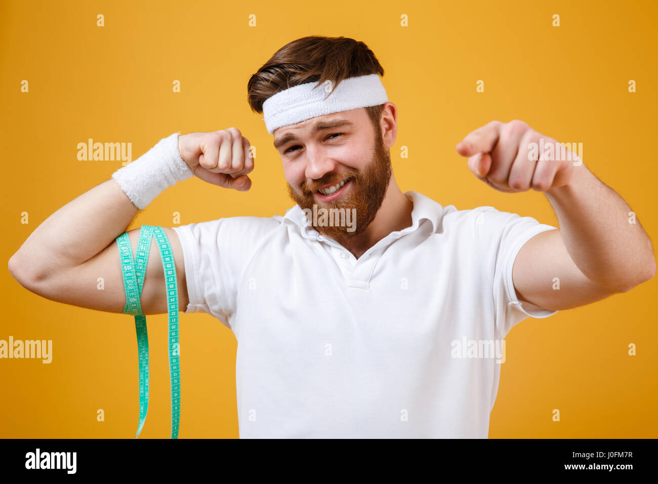 Portrait of a smiling confident sports man measuring his biceps and ...