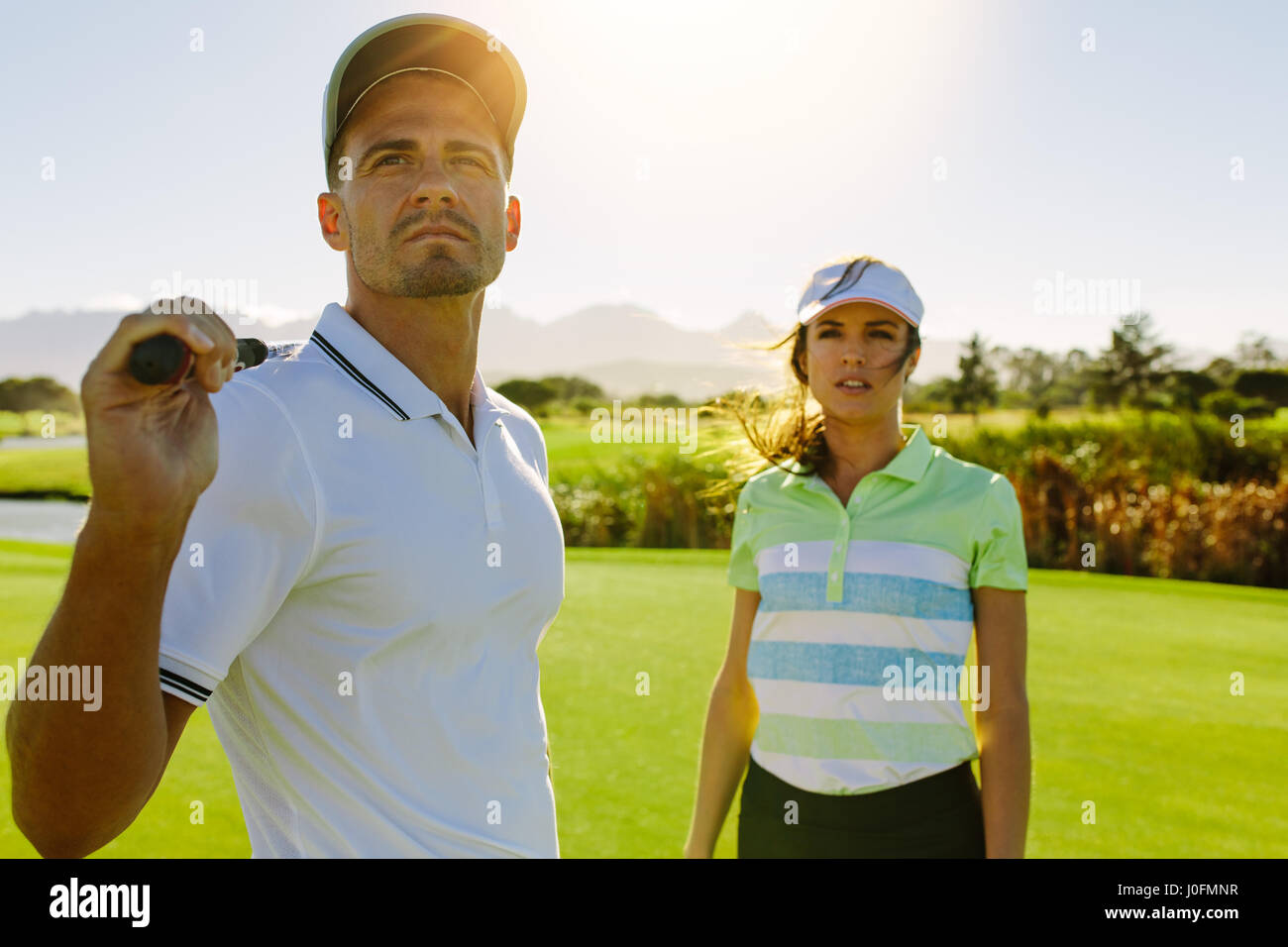 Young golfers at golf course together. Male and female golf players on ...