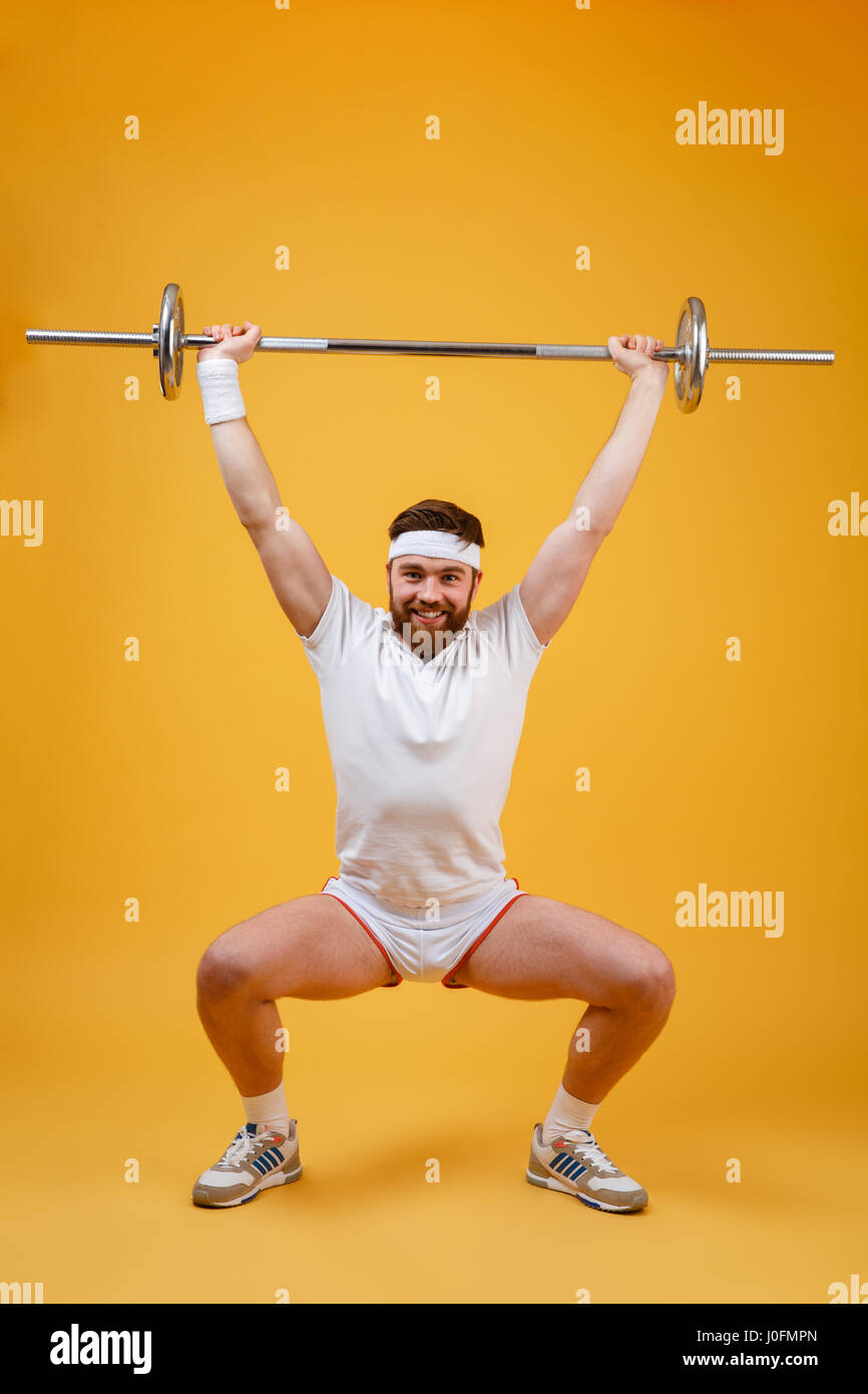 Full length portrait of athletic man doing squatting exercises with ...