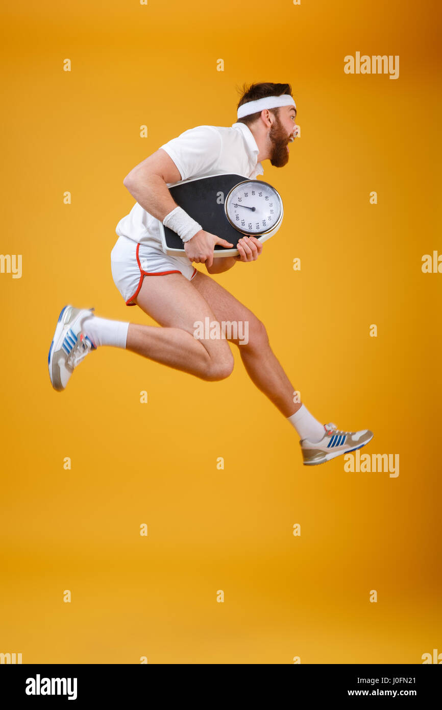 Image of screaming young sportsman jumping holding scales dressed in ...